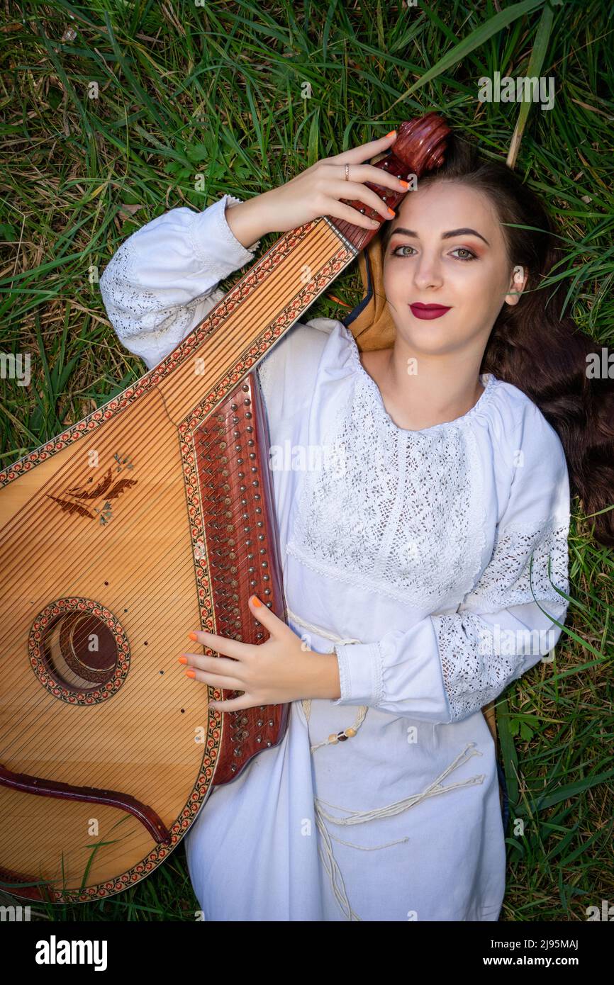 Ukrainian girl lying on the grass in a white embroidered dress with the ...