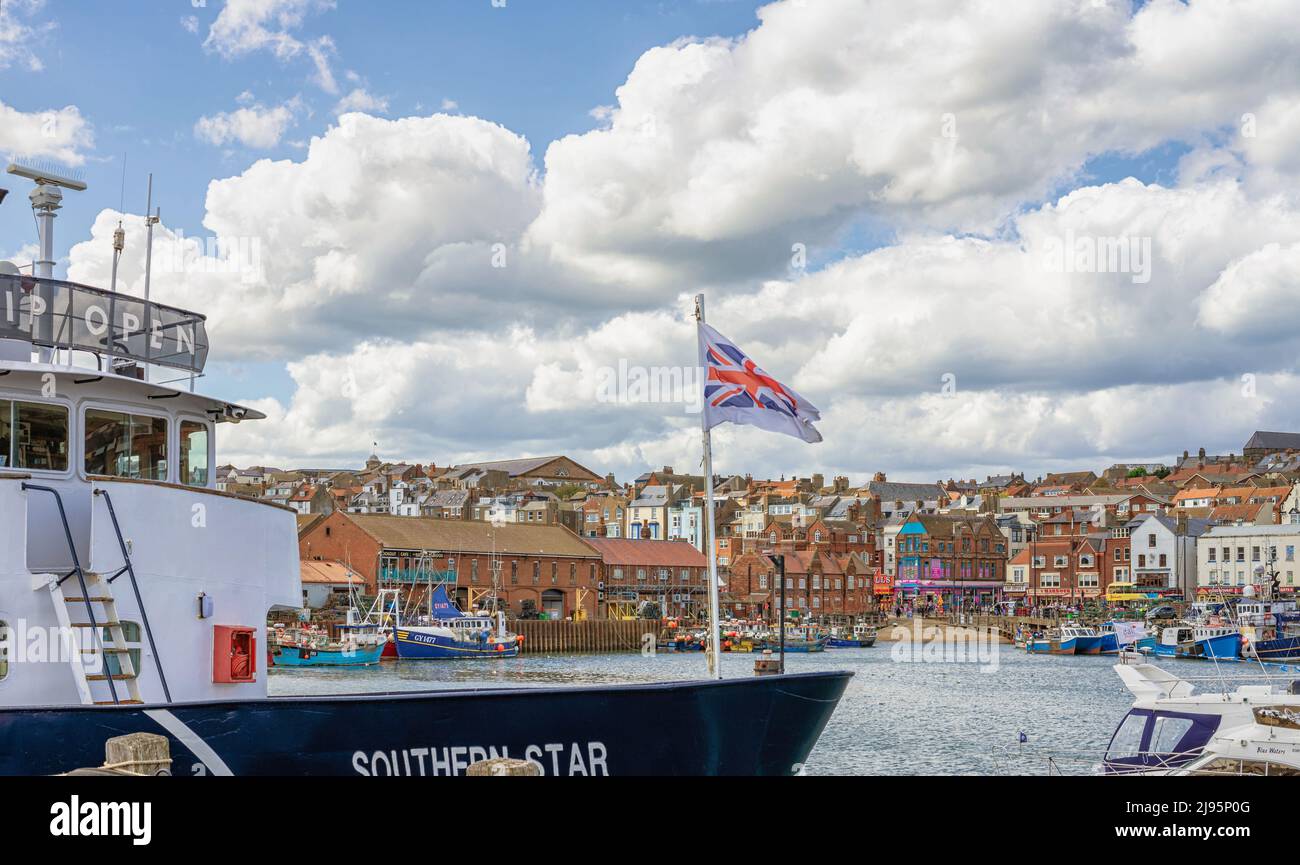 A ship is moored in harbour and flying the union flag from its bow. A ...