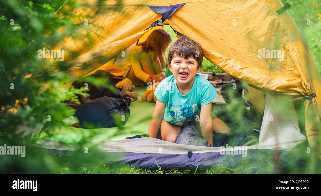 Small children, kids play, read in orange tourist tent. Family trip ...