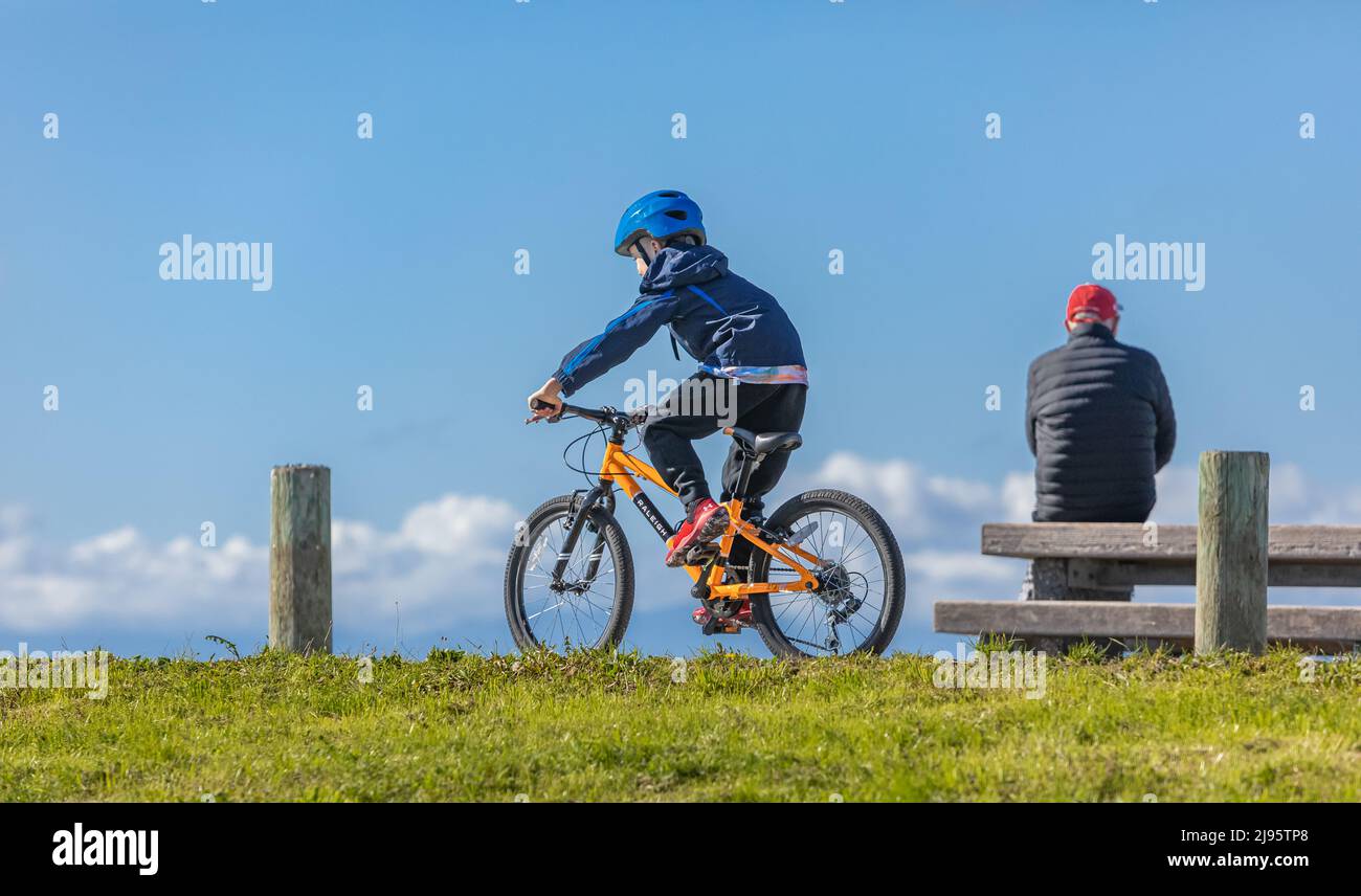 A boy rides on a bicycle wearing helmet in the summer park. Happy kid ...