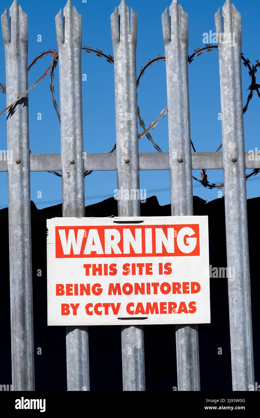 CCTV warning being monitored sign and spiked barbed wire fence Stock ...