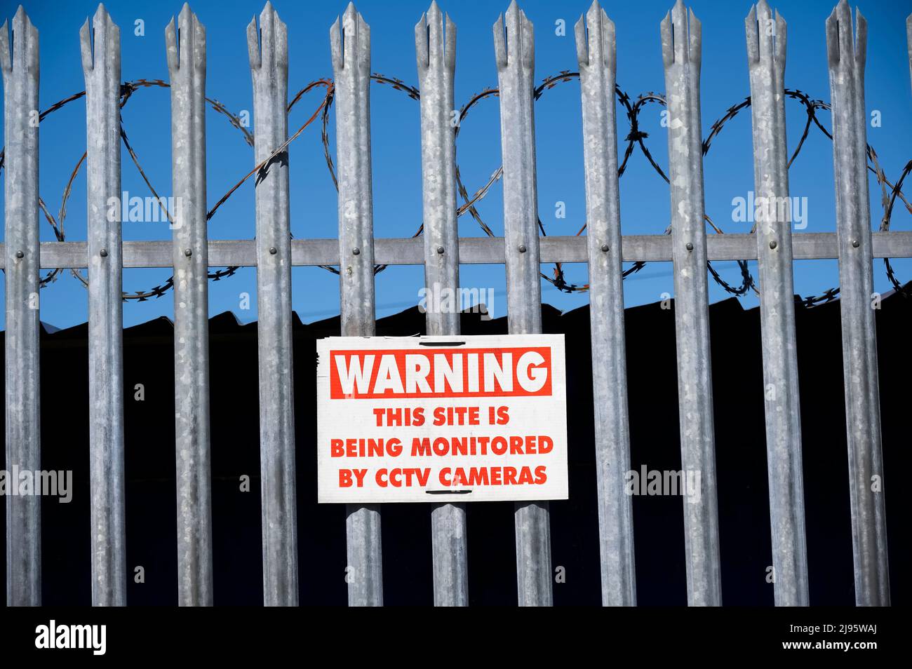 CCTV warning being monitored sign and spiked barbed wire fence Stock ...