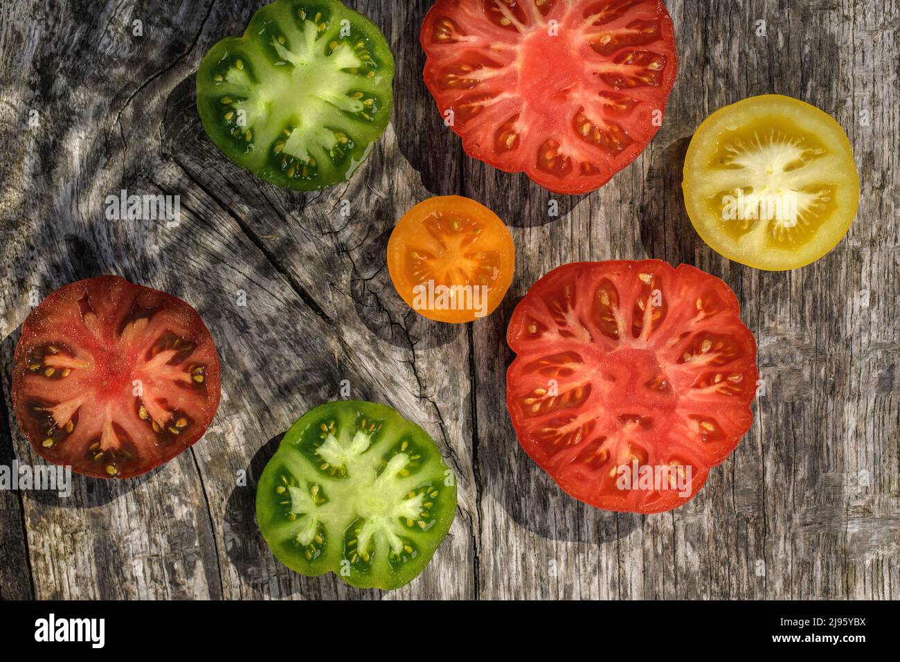 Variety of ripe organic tomatoes of different colours on aged wood ...