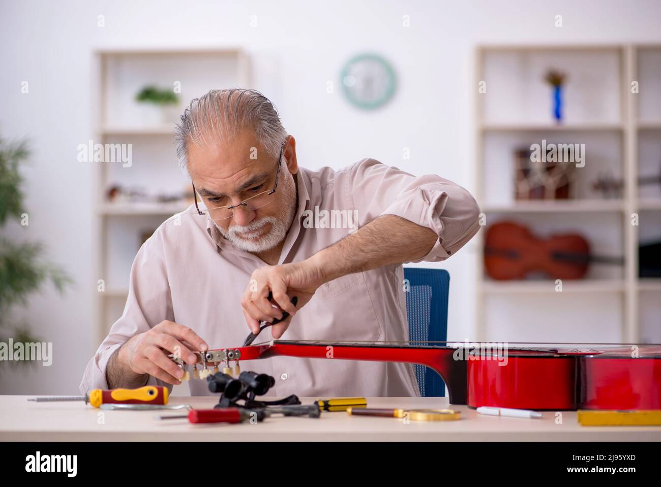Old repairman repairing musical instruments at workshop Stock Photo - Alamy