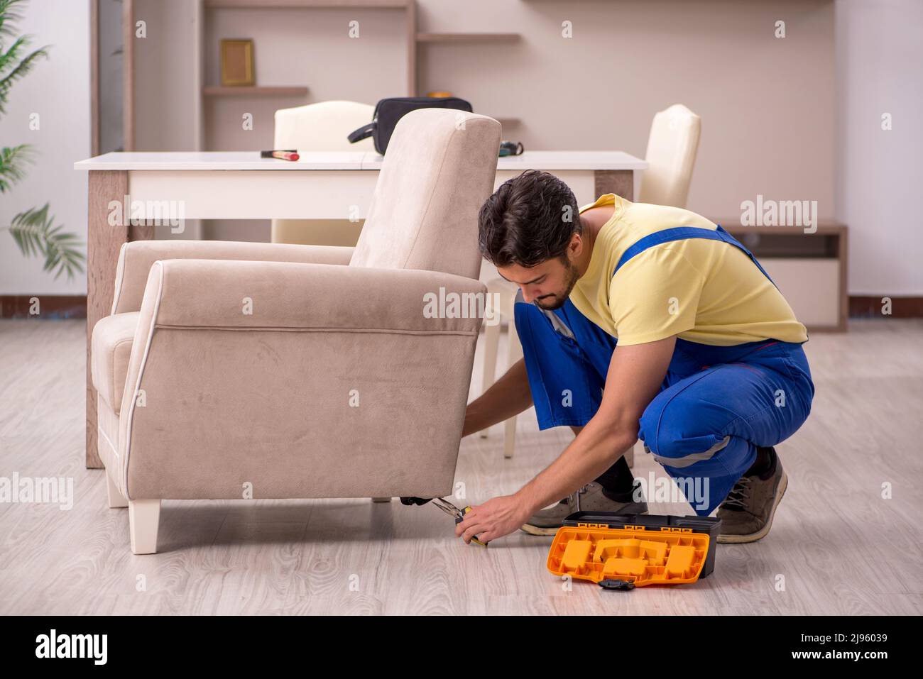 Young carpenter repairing arm-chair at home Stock Photo - Alamy