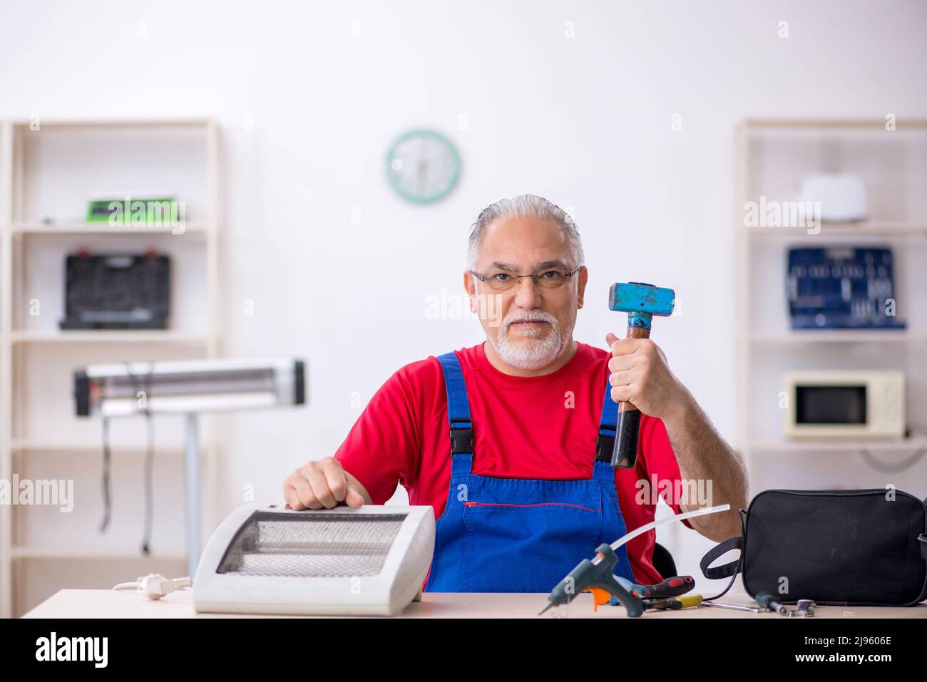 Old male repairman repairing heater at workshop Stock Photo - Alamy