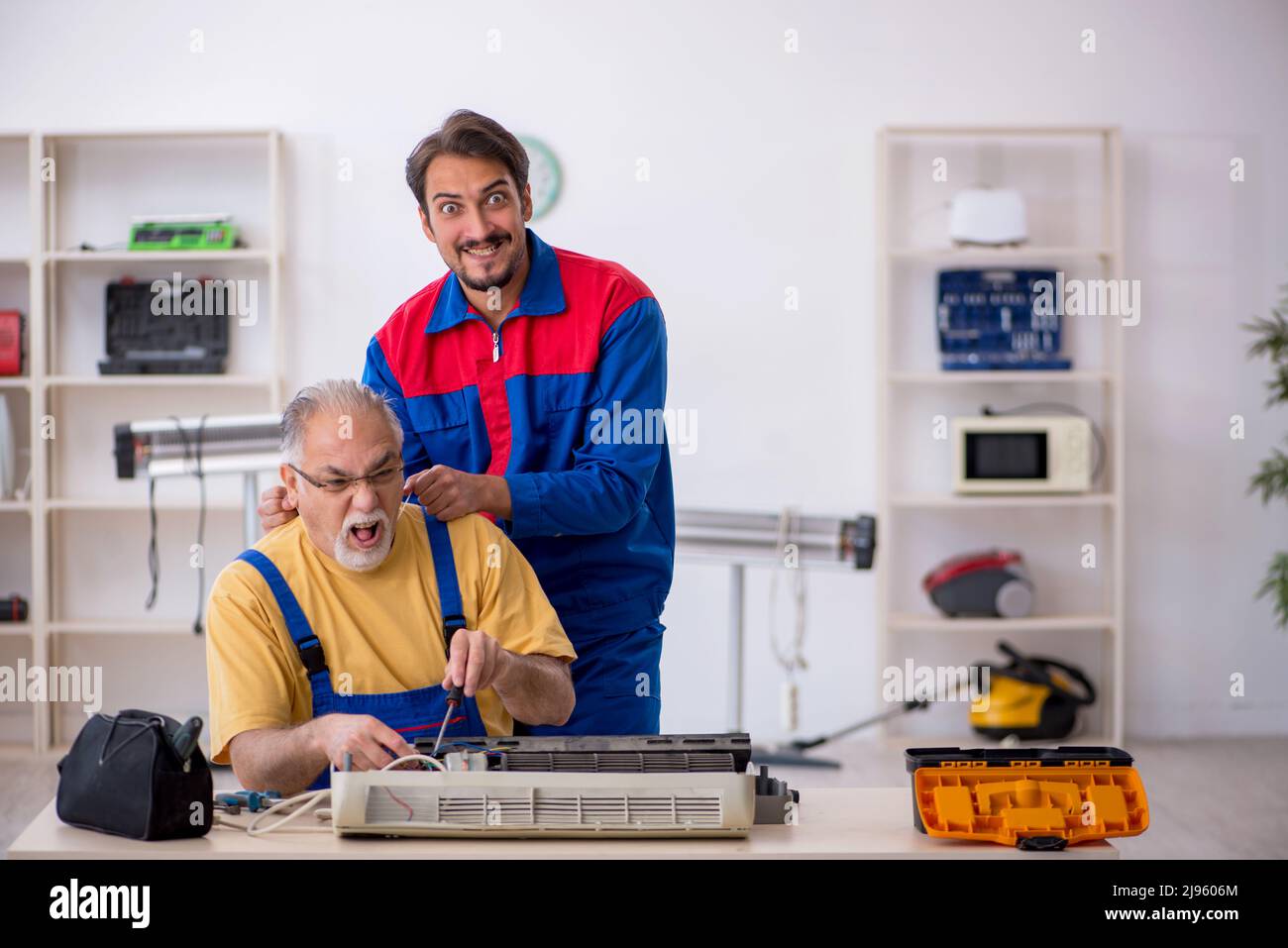 Two repairmen repairing air-conditioner at workshop Stock Photo - Alamy