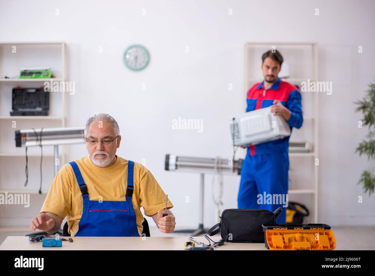 Two repairmen working at workshop Stock Photo - Alamy