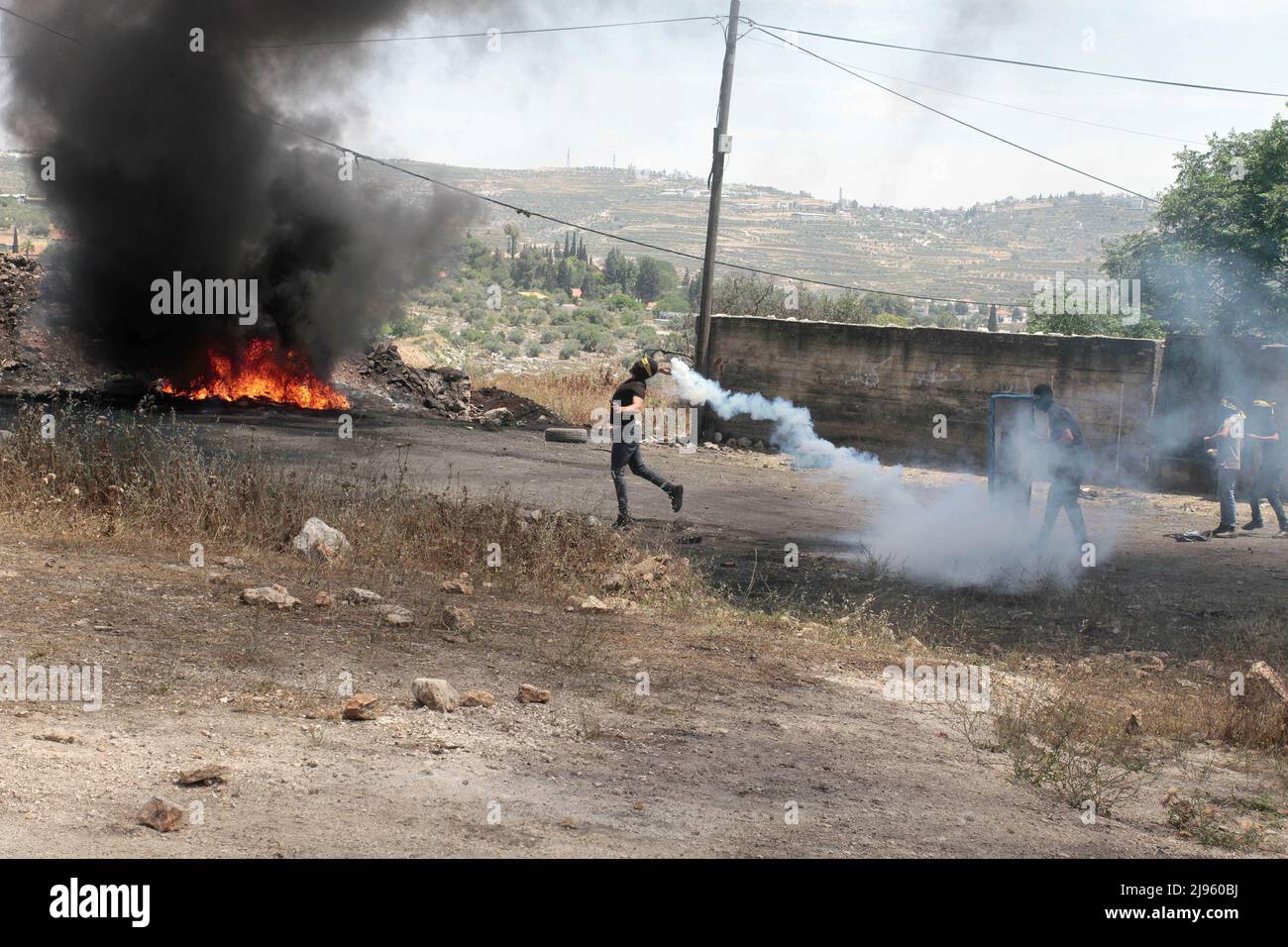 Nablus, Palestine. 12th May, 2022. A Palestinian protester throws back ...