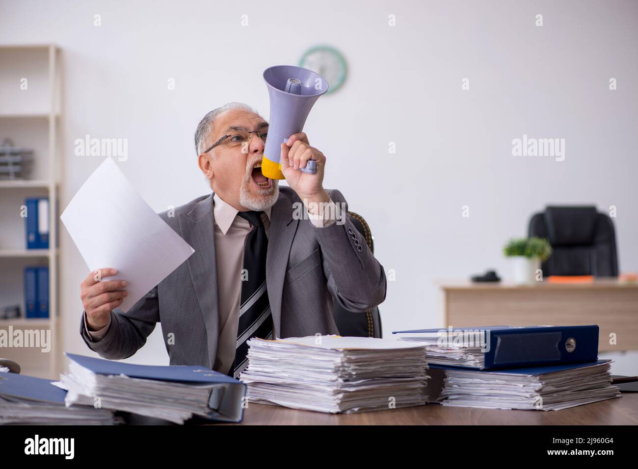 Old male boss holding megaphone at workplace Stock Photo - Alamy