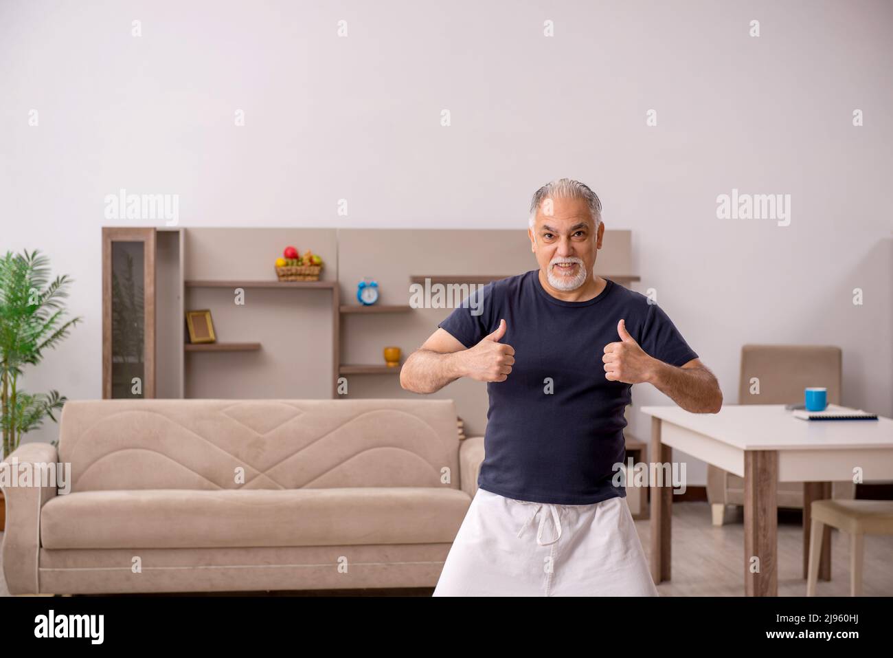 Old man doing sport exercises indoors Stock Photo - Alamy
