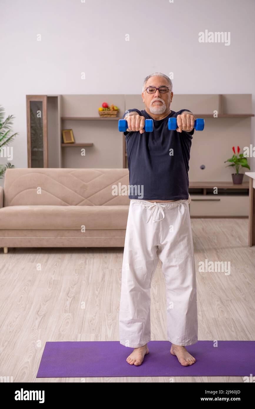 Old man doing sport exercises indoors Stock Photo - Alamy