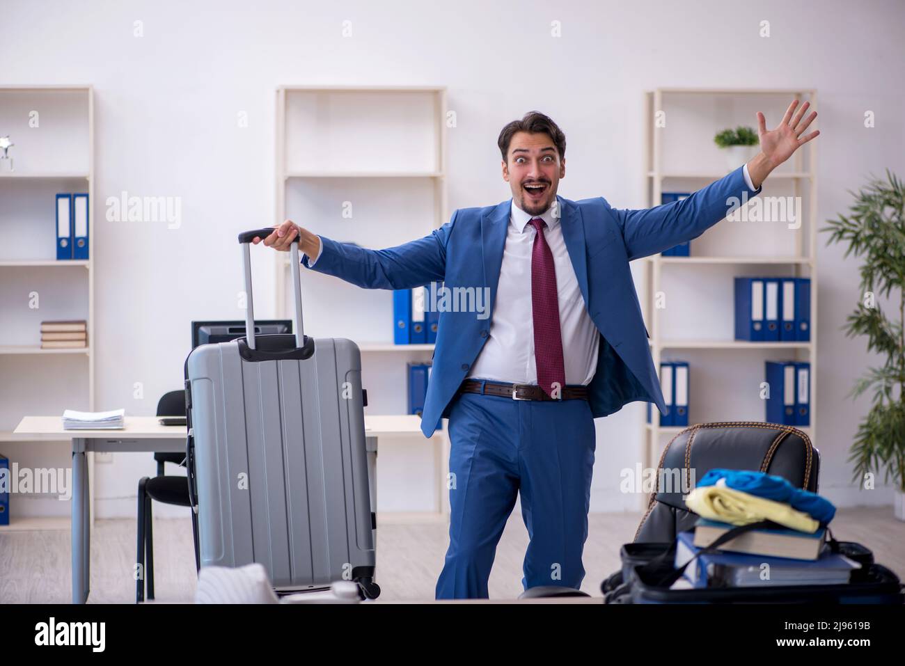 Young businessman employee preparing for trip at workplace Stock Photo ...