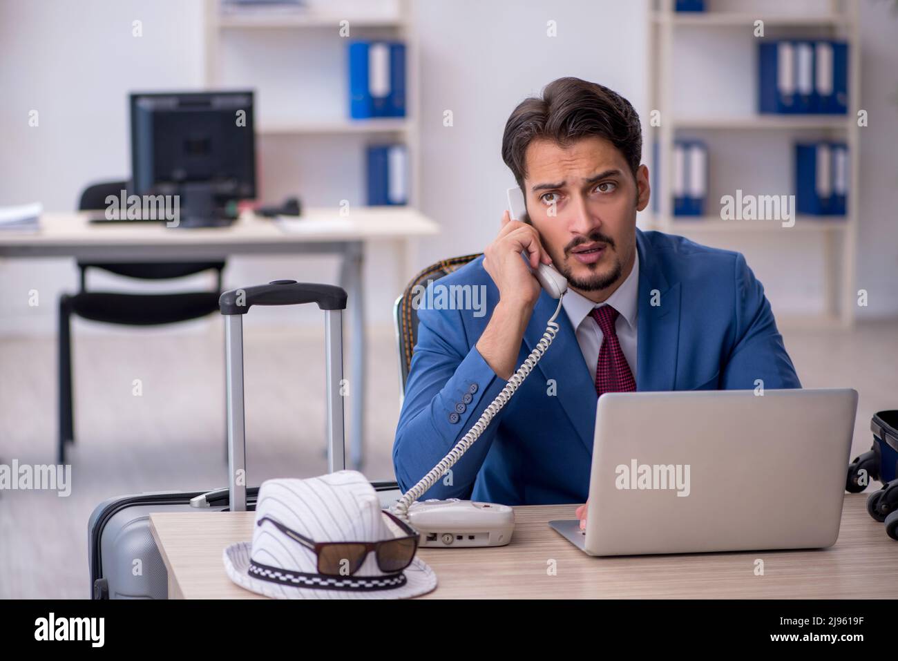 Young businessman employee preparing for trip at workplace Stock Photo ...