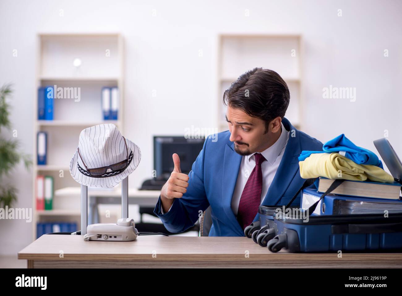 Young businessman employee preparing for trip at workplace Stock Photo ...