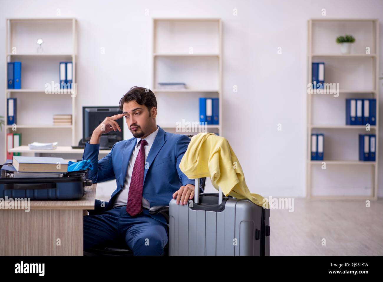 Young businessman employee preparing for trip at workplace Stock Photo ...