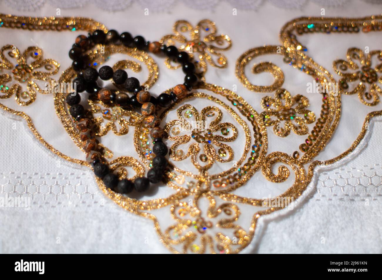 Two rosaries and traditional gold-coloured embroidery Stock Photo - Alamy