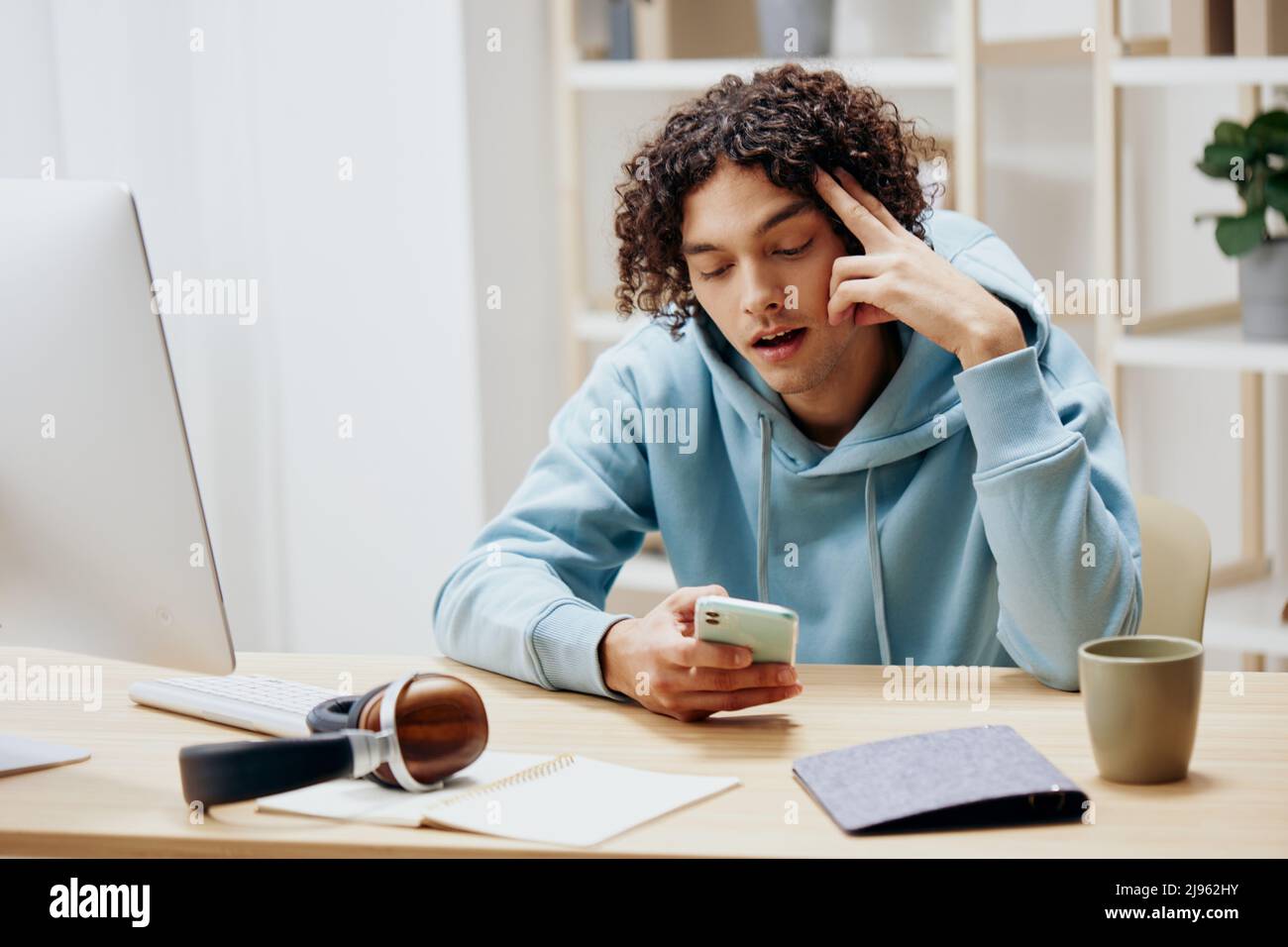 handsome guy in a blue jacket in front of a computer with phone ...