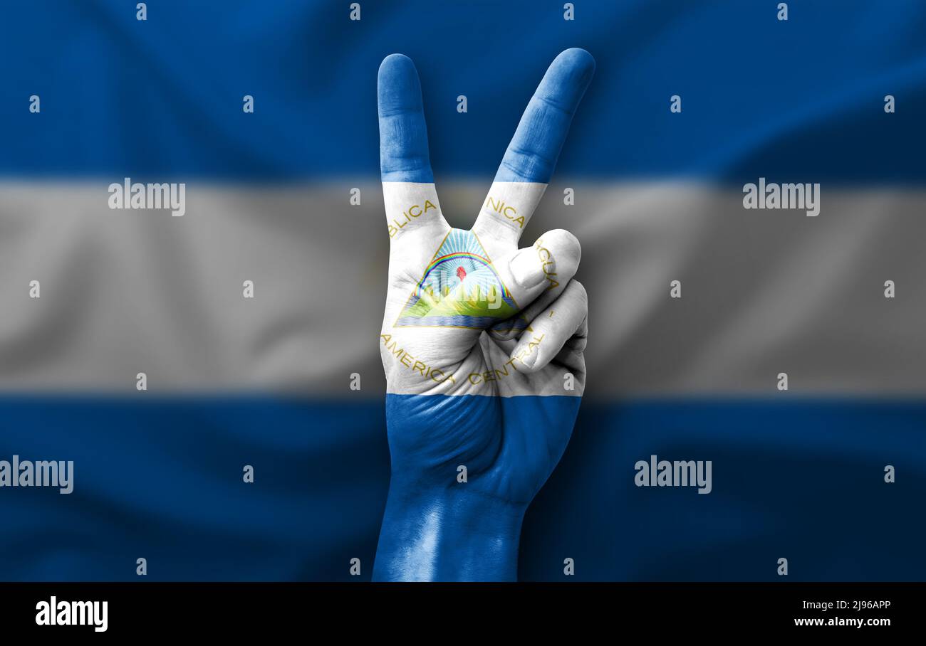 Hand making the V victory sign with flag of nicaragua Stock Photo - Alamy