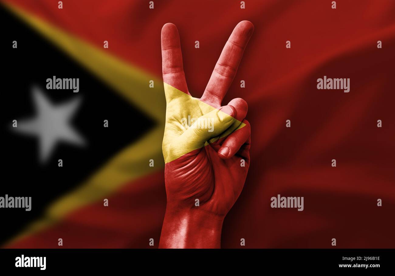 Hand making the V victory sign with flag of timor leste Stock Photo - Alamy