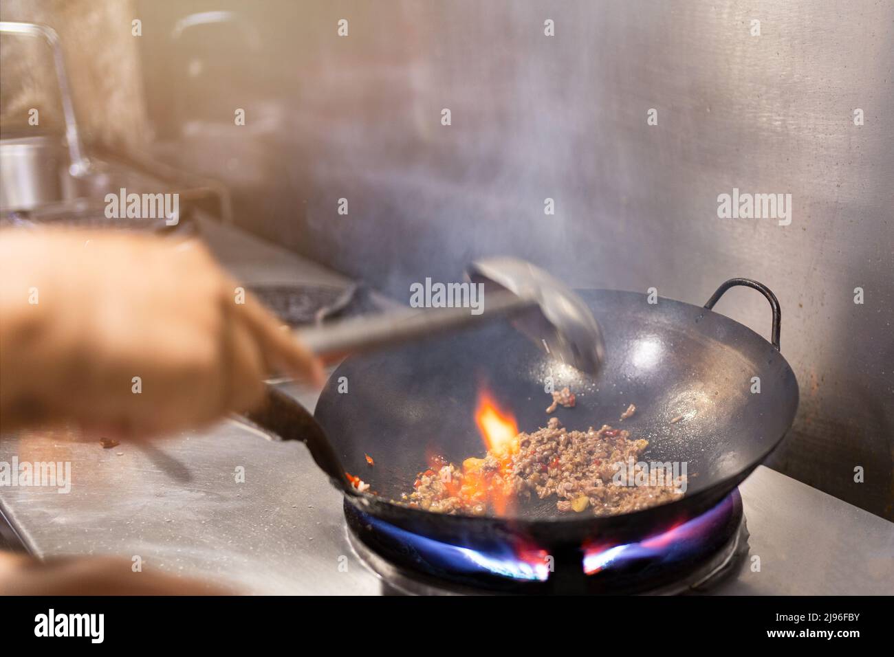 Chef stir fry in wok. Dramatic cooking with fire hard Stock Photo - Alamy