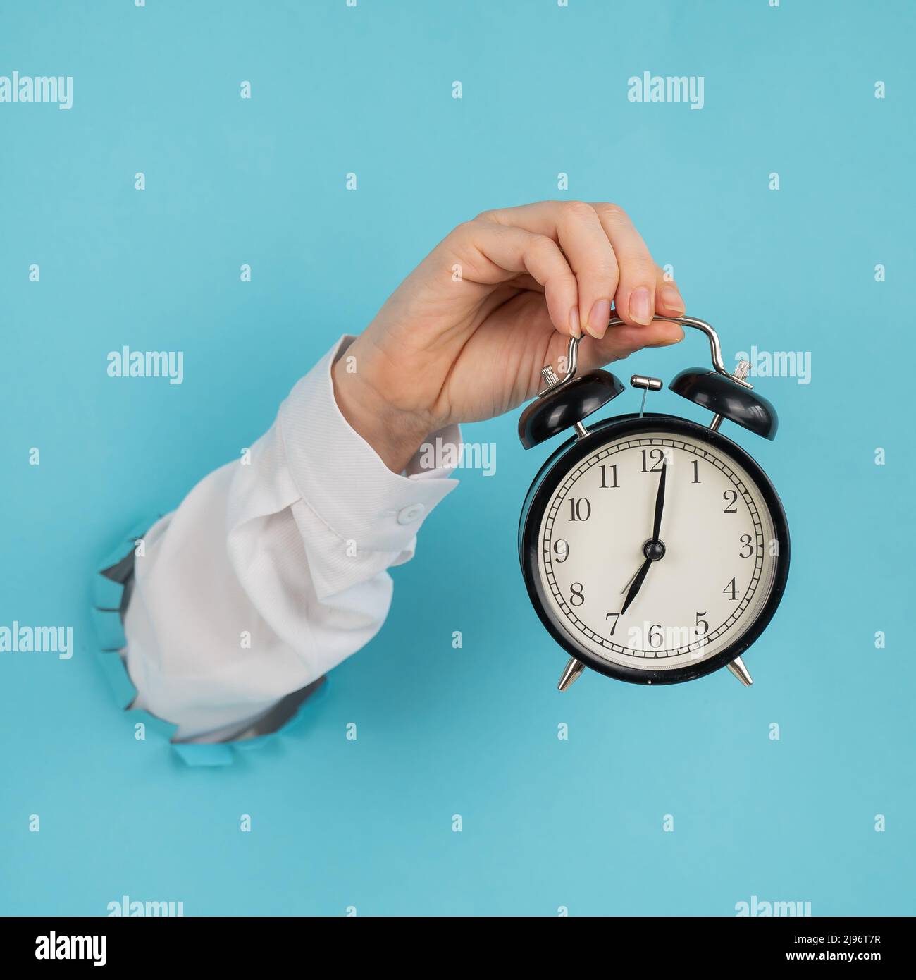 A woman's hand sticks out of a hole in a blue paper background and ...