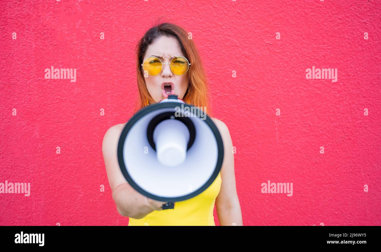 Indignant woman in sunglasses shouts into a megaphone on a red ...