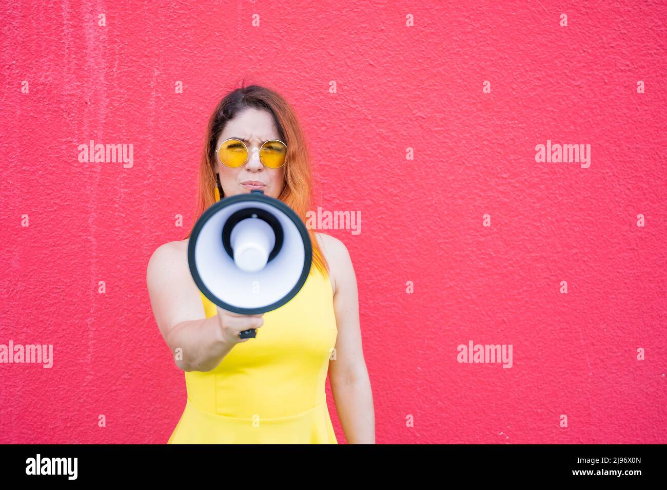 Indignant woman in sunglasses shouts into a megaphone on a red ...