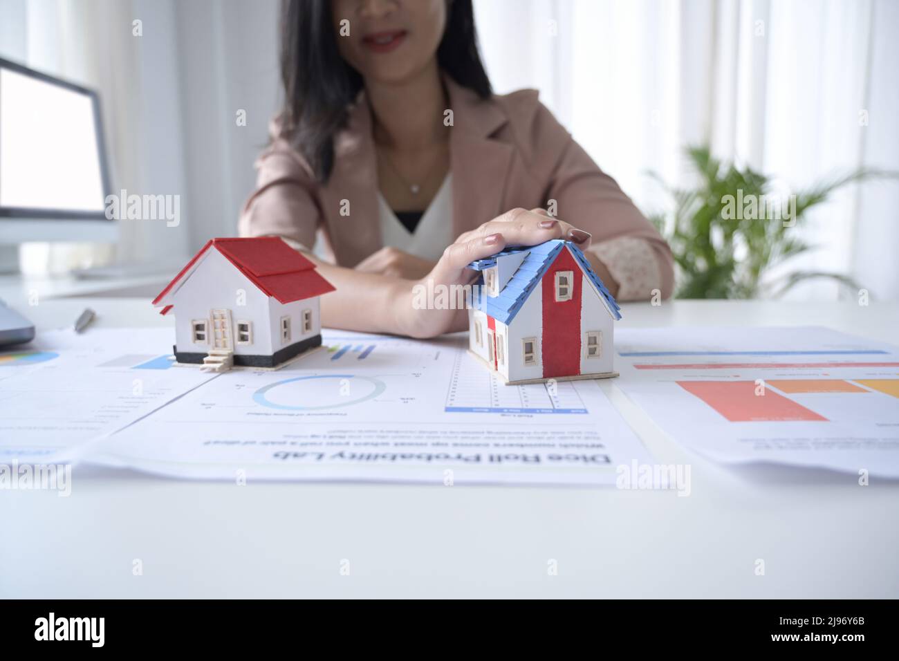Real estate agent with small house model and documents on white office ...