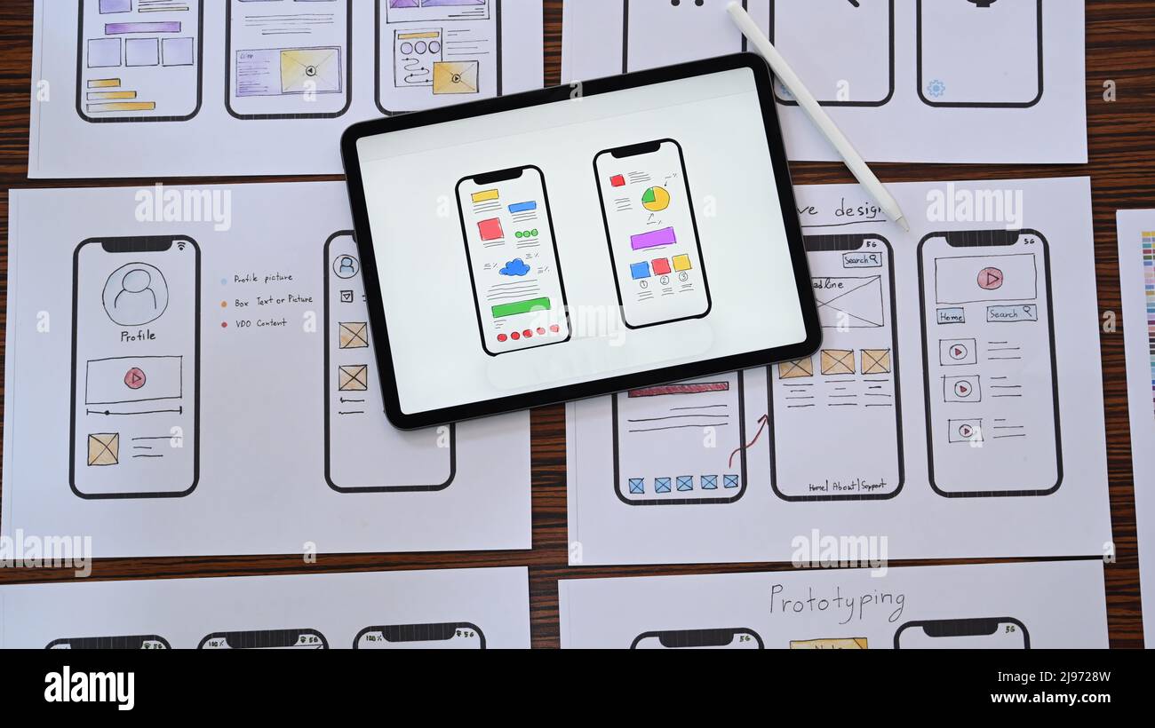 Web developer workplace with sketches of mobile application on wooden ...