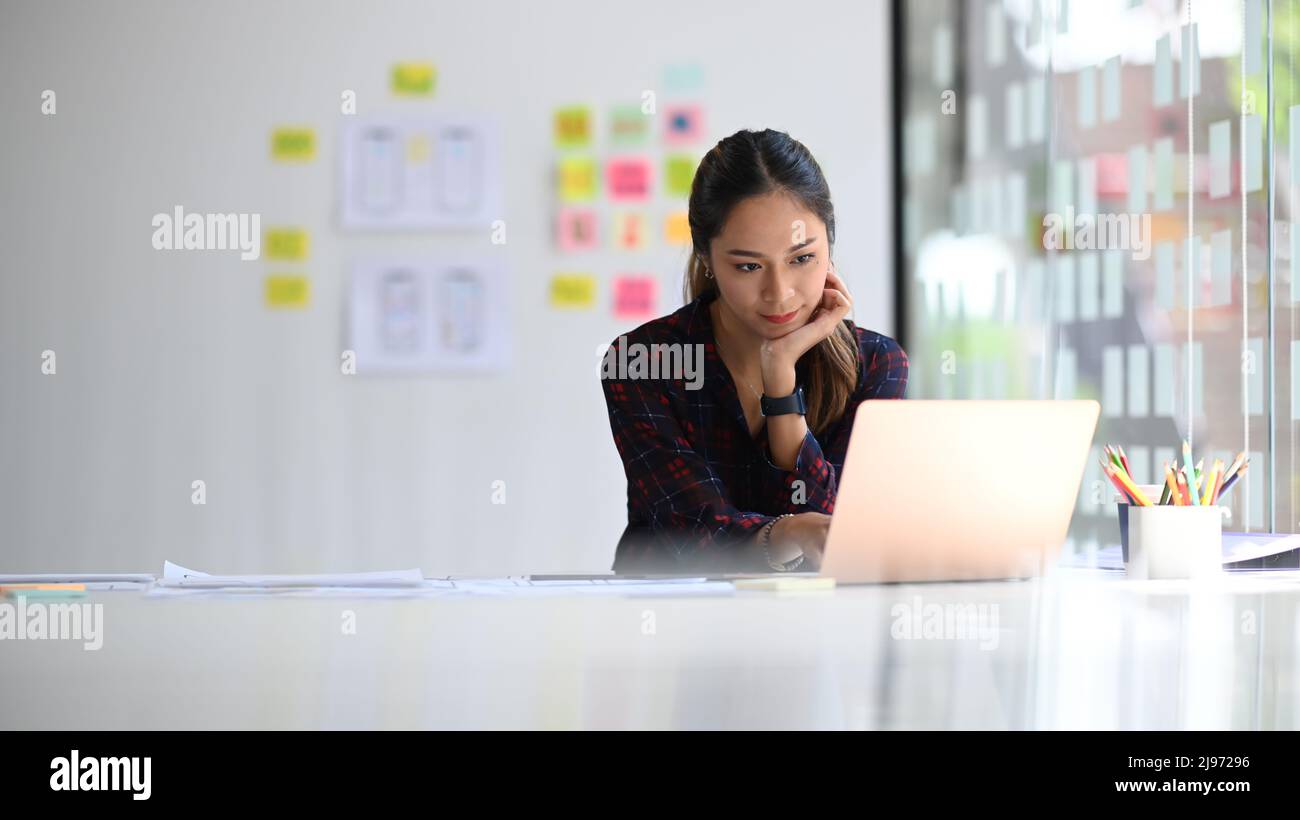 Concentrated female web developer working on mobile application software design project at ...