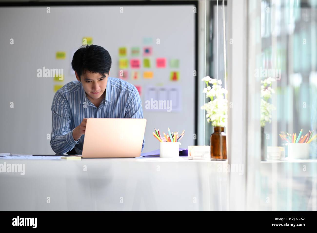 Young asian male web developer working on mobile application software ... Young asian male web developer working on mobile application software ...