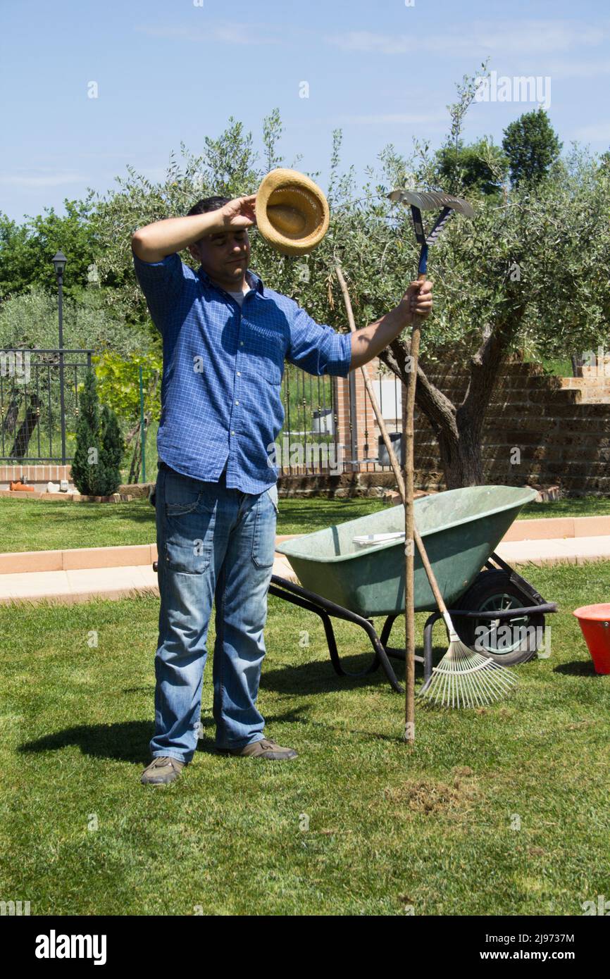 Image of a tired gardener who wipes sweat from his forehead in the ...