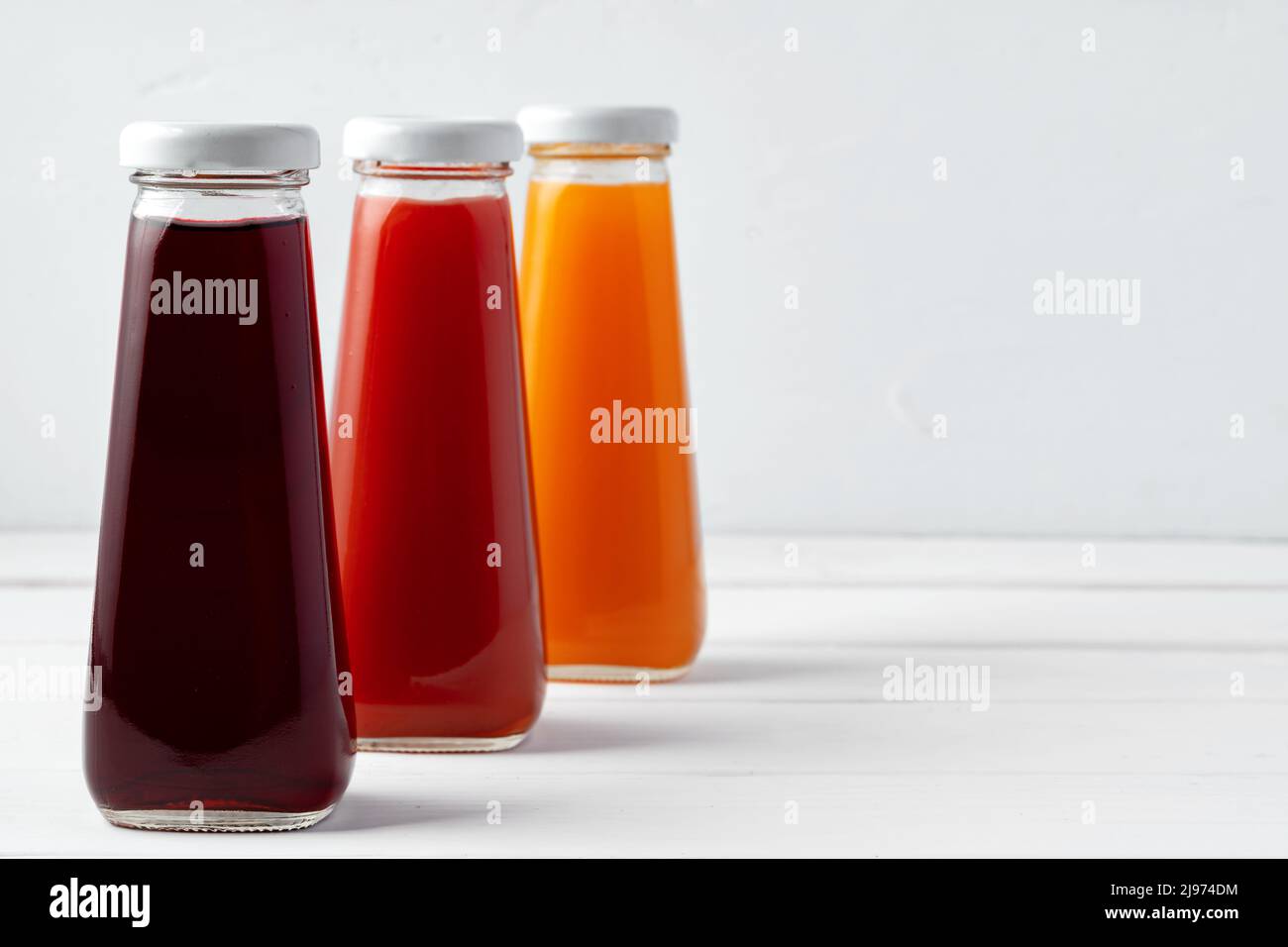 Glass bottles of different juices on white background Stock Photo - Alamy