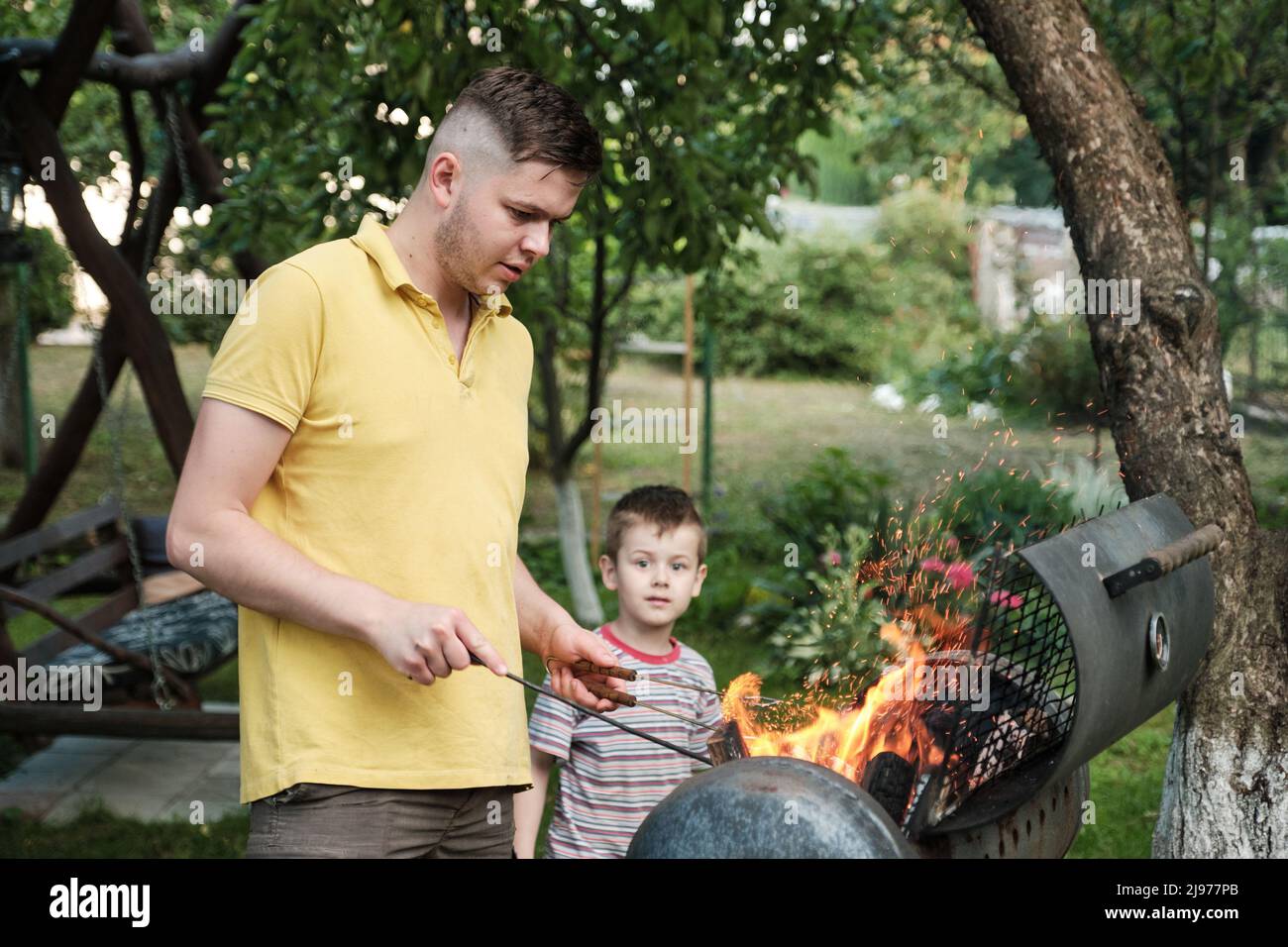 Young man putting firewood in mangal. Handsome athlete male builds a ...