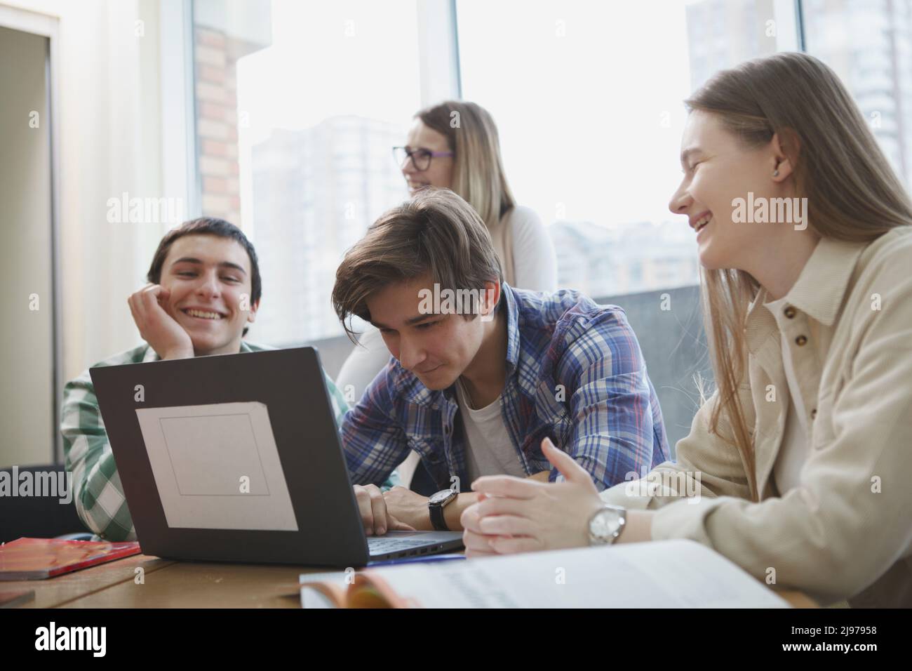 Young people having fun, studying together in college, using laptop in ...