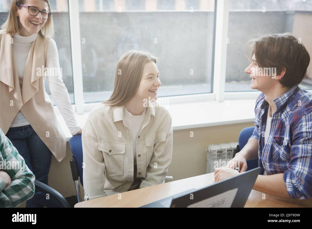 Cheerful college students and their teacher laughing, having discussion ...