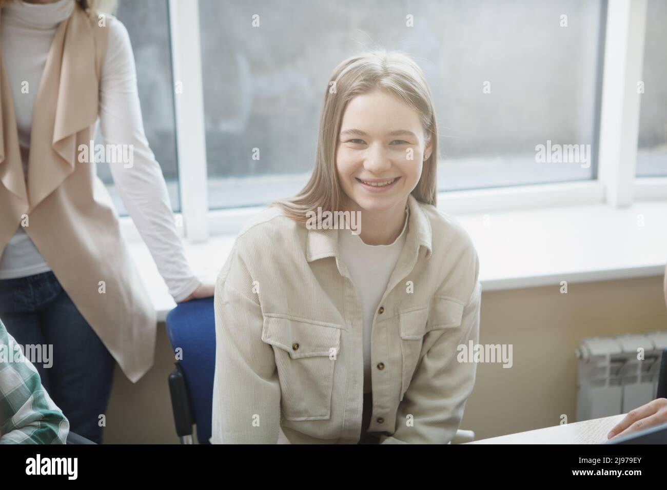Charming young female college student smiling, sitting in a classroom ... Charming young female college student smiling, sitting in a classroom ...