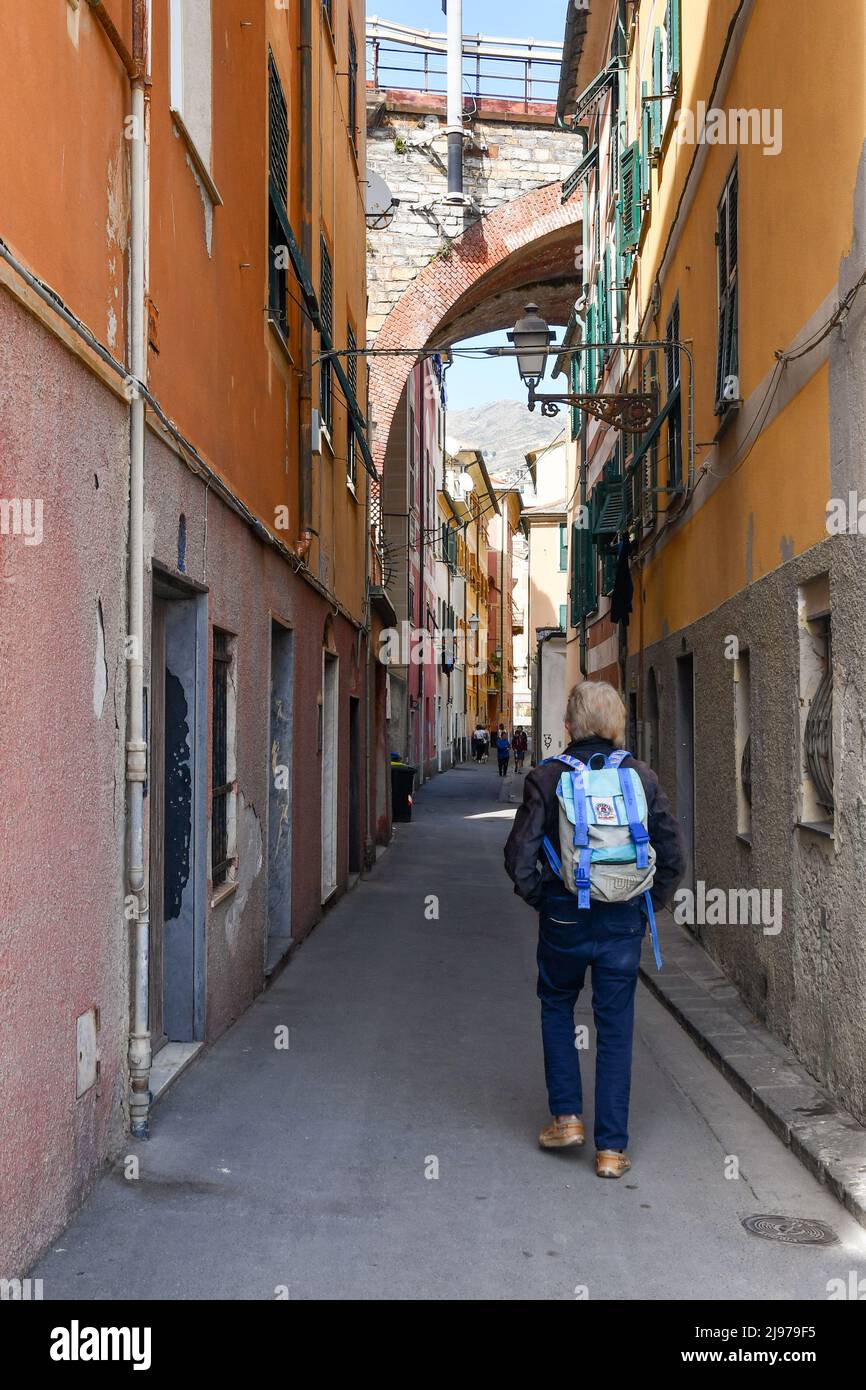 Backpacker from behind walking in a typical narrow alley ("caruggio ...