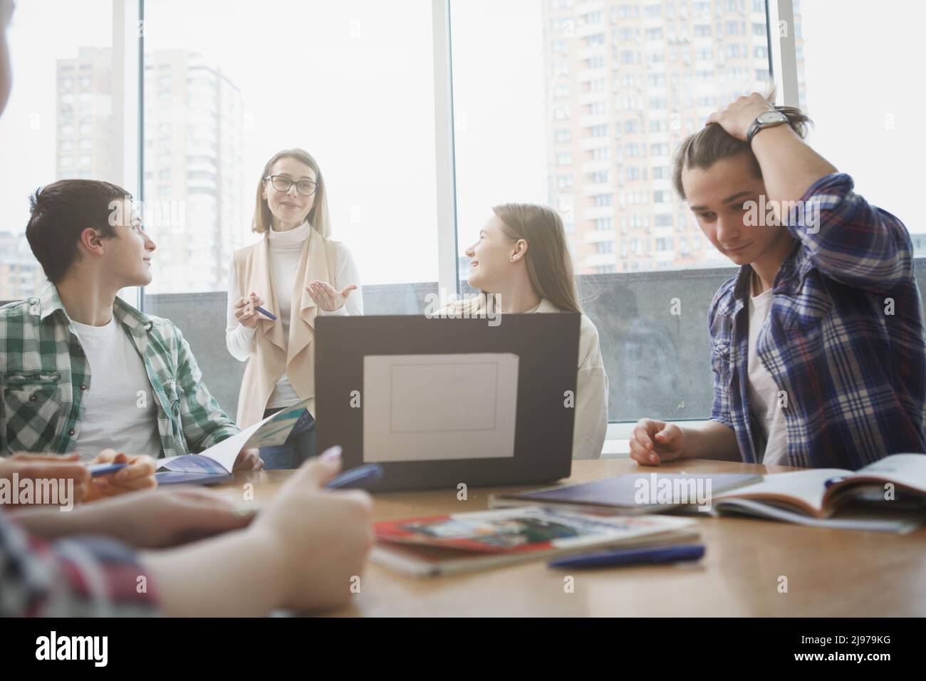 Happy college students enjoying learning from their experienced female ...