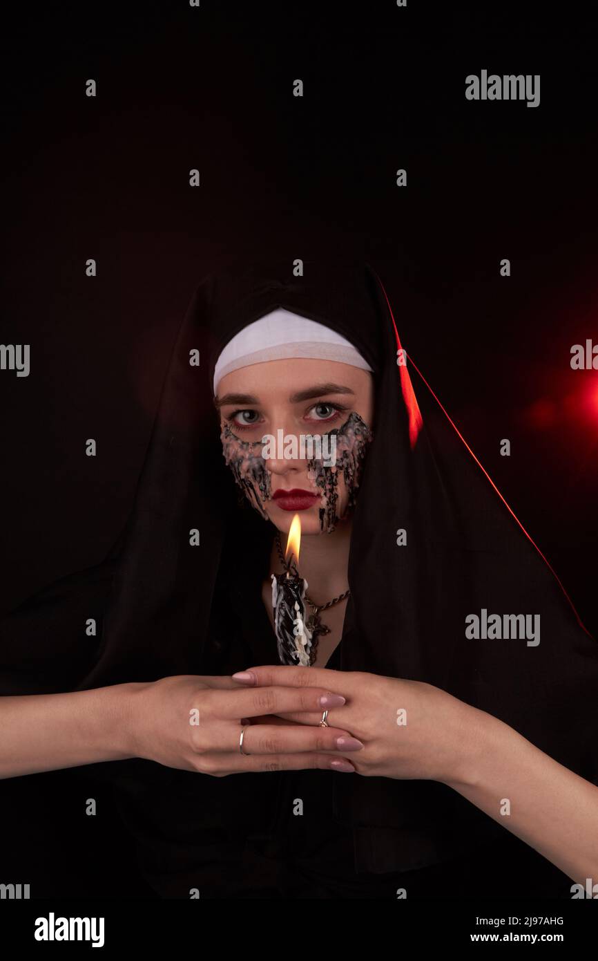 Portrait of a young gothic girl holds burning candle in the dark. Woman ...
