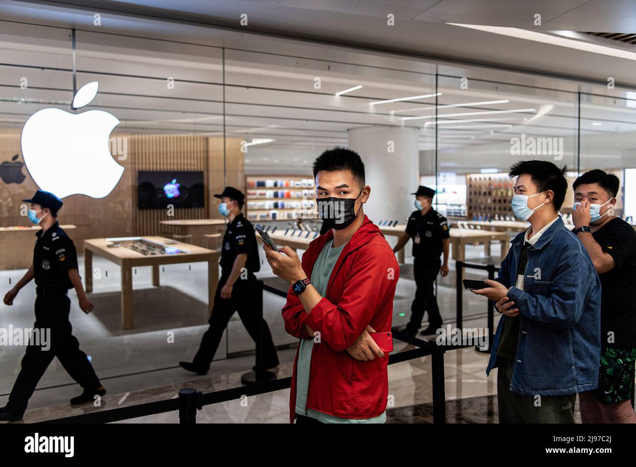 People wearing masks wait in line following social distancing rules at ...
