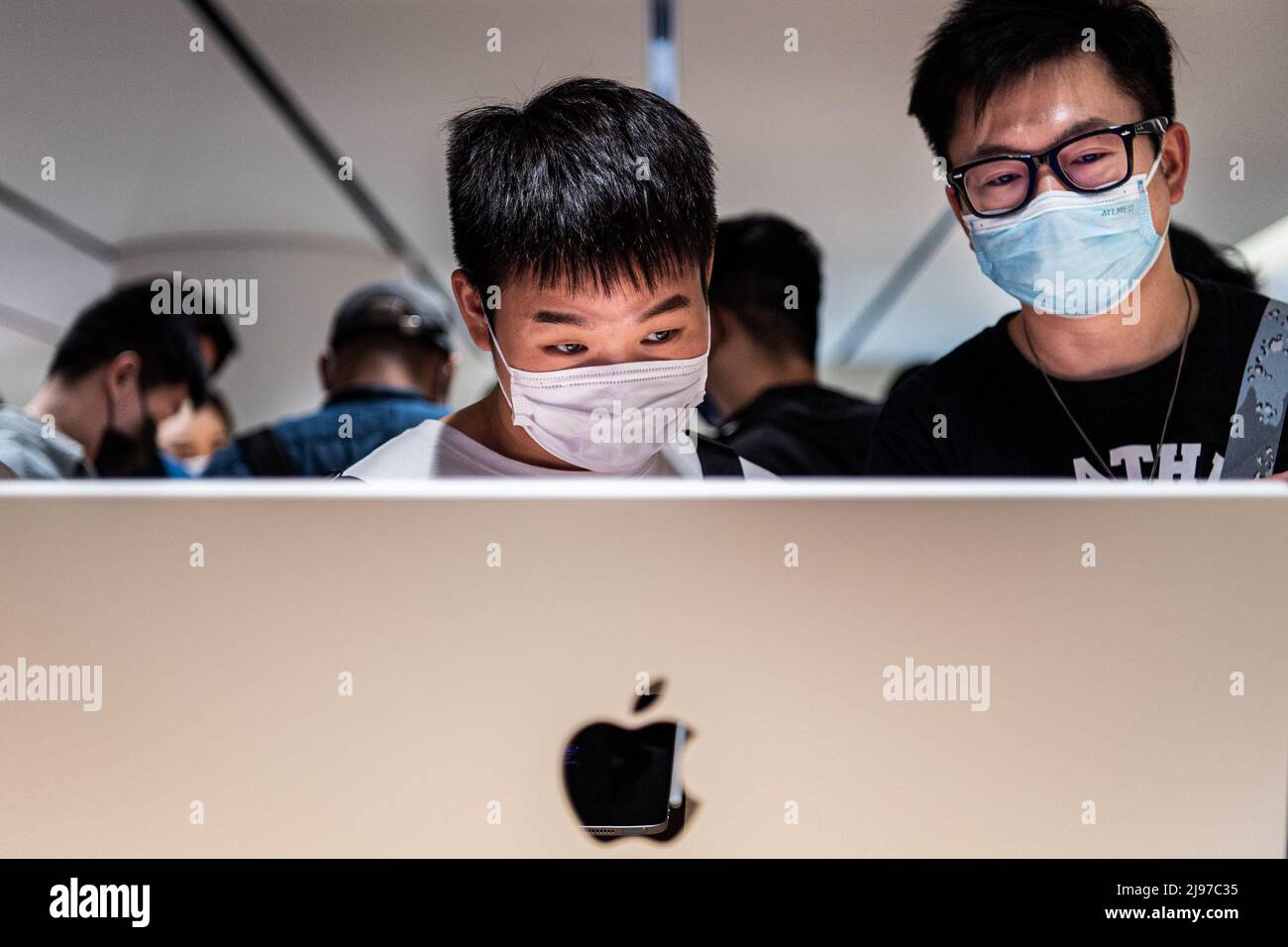 Chinese customers wearing masks try an iMac at the official opening of ...