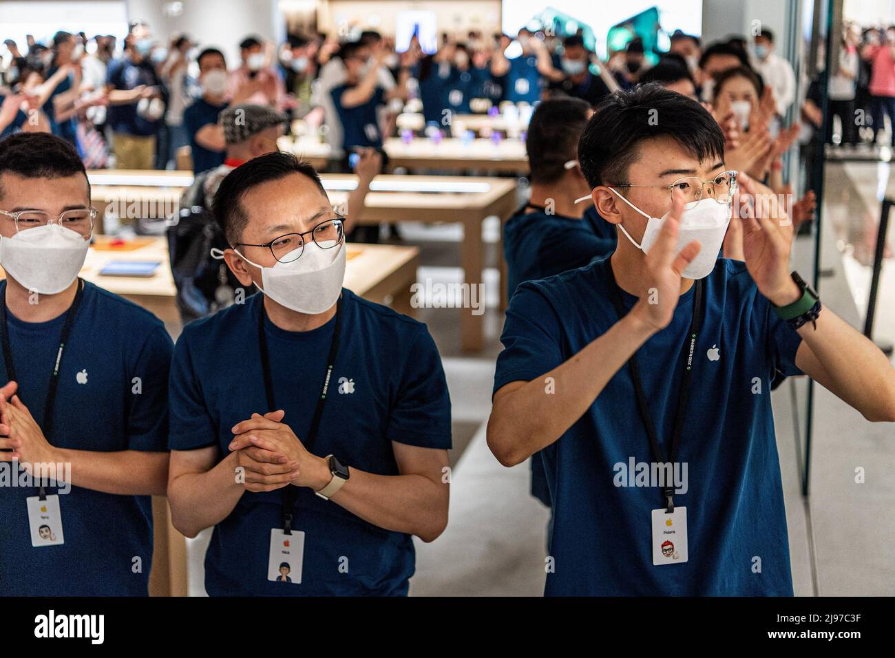 Apple staff wearing masks welcome customers at the opening of a new ...