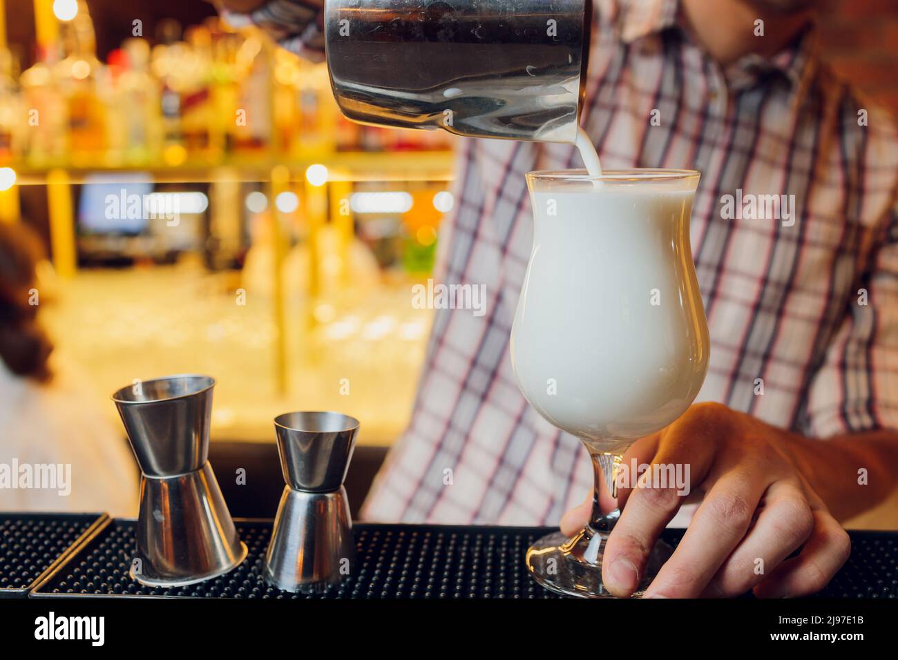 Close up shot of bartender hand pouring Cream mocktail in a glass from shaker Stock Photo - Alamy