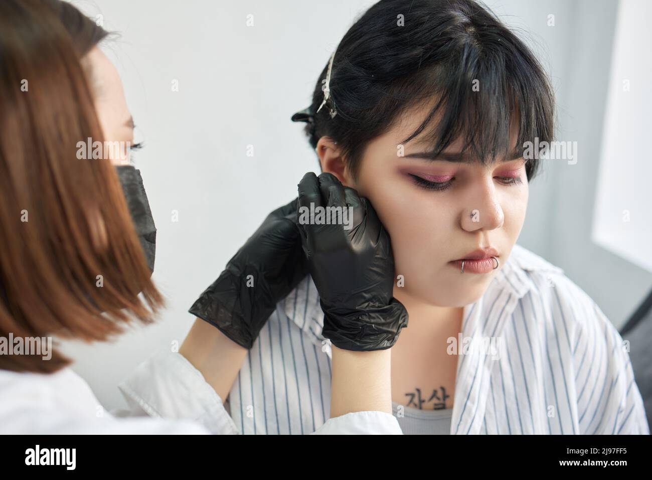 A beautician makes a puncture of the earlobe with a disposable device ...