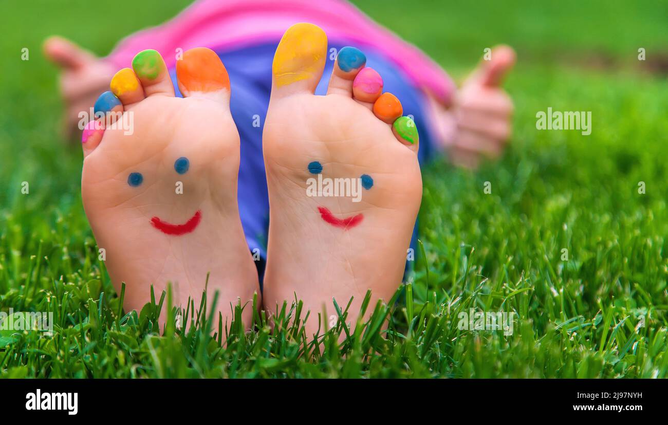 Feet of a child on the grass with a painted smile. Selection focus ...