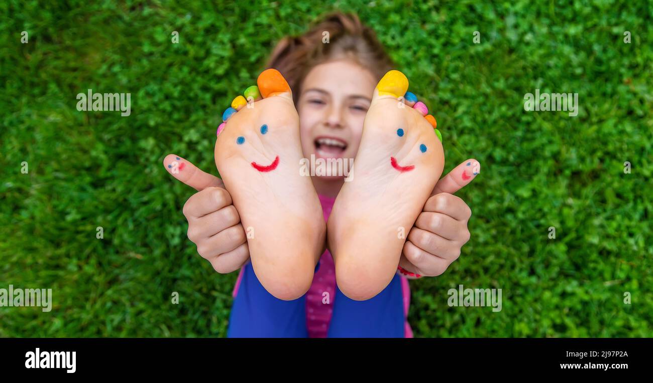 Feet of a child on the grass with a painted smile. Selection focus ...