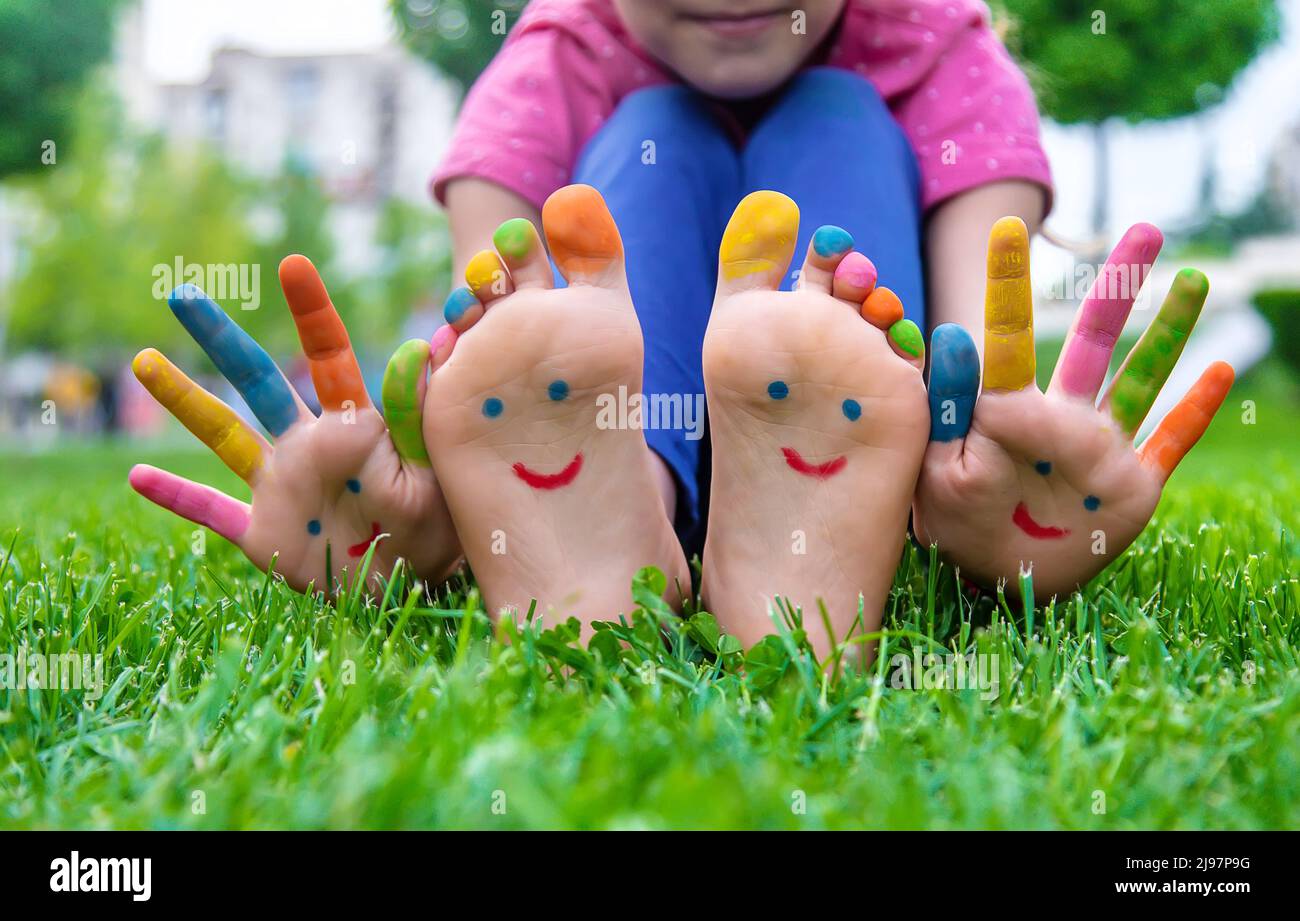Feet of a child on the grass with a painted smile. Selection focus ...