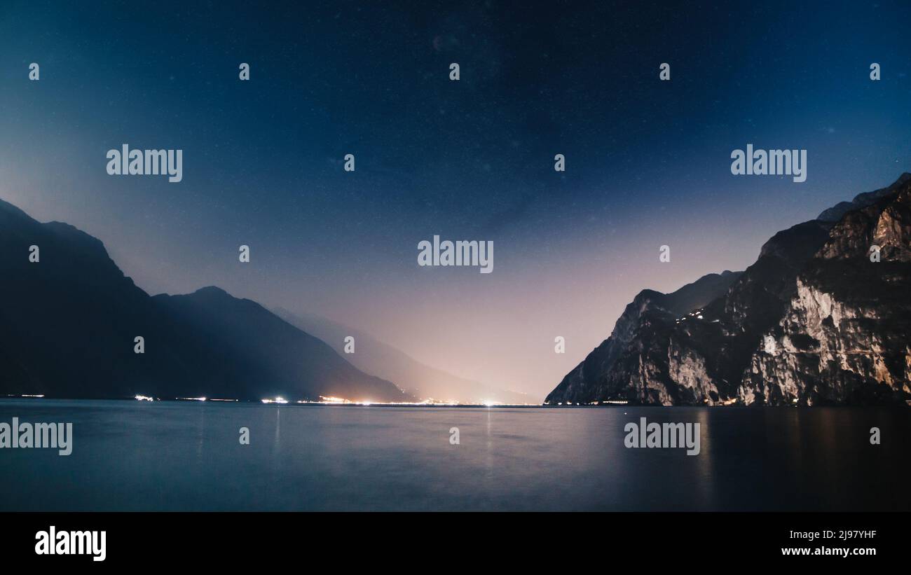 a grainy wide shot of a lake between two mountains at night with a star ...